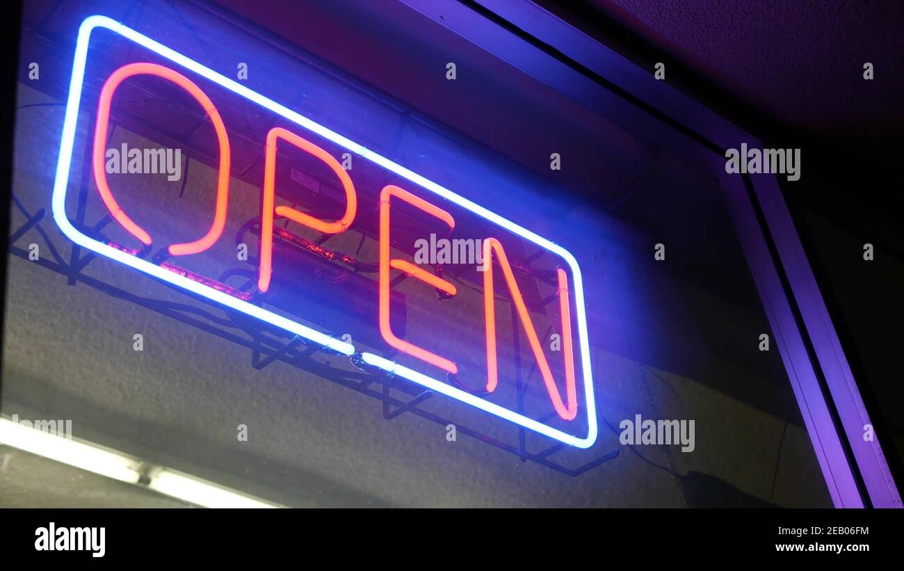 Open neon sign glowing in the dark. Vivid retro styled text at entrance ...