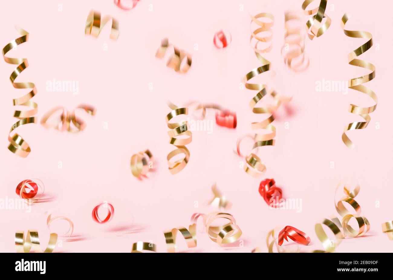 Golden and red flying confetti streamer on pink background Stock Photo ...