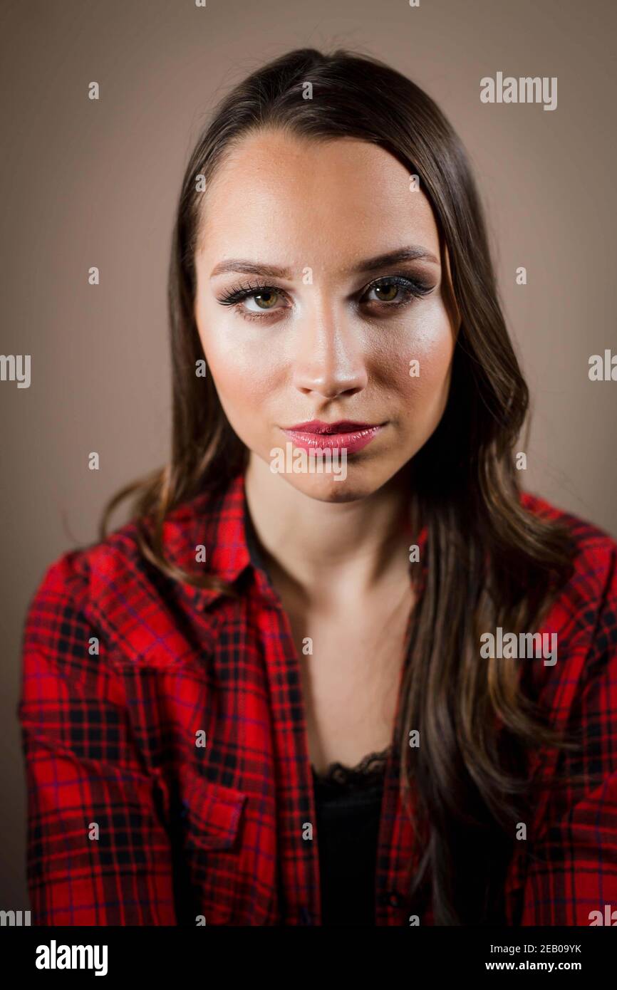 Portrait of a beautiful female with a po face on a brown background ...