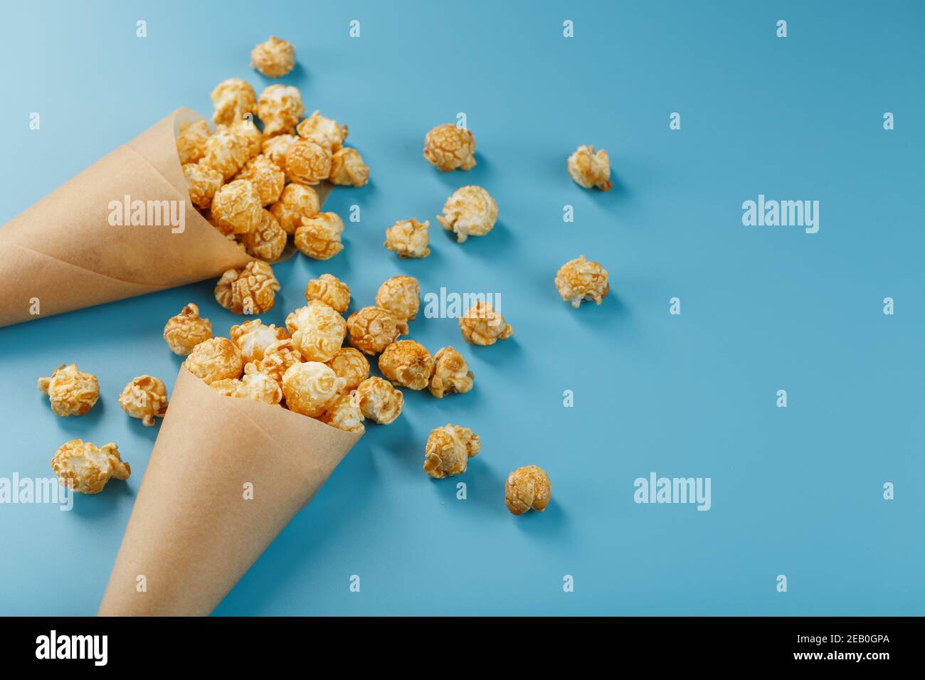 Caramel popcorn in a paper envelope on a blue background. Delicious ...