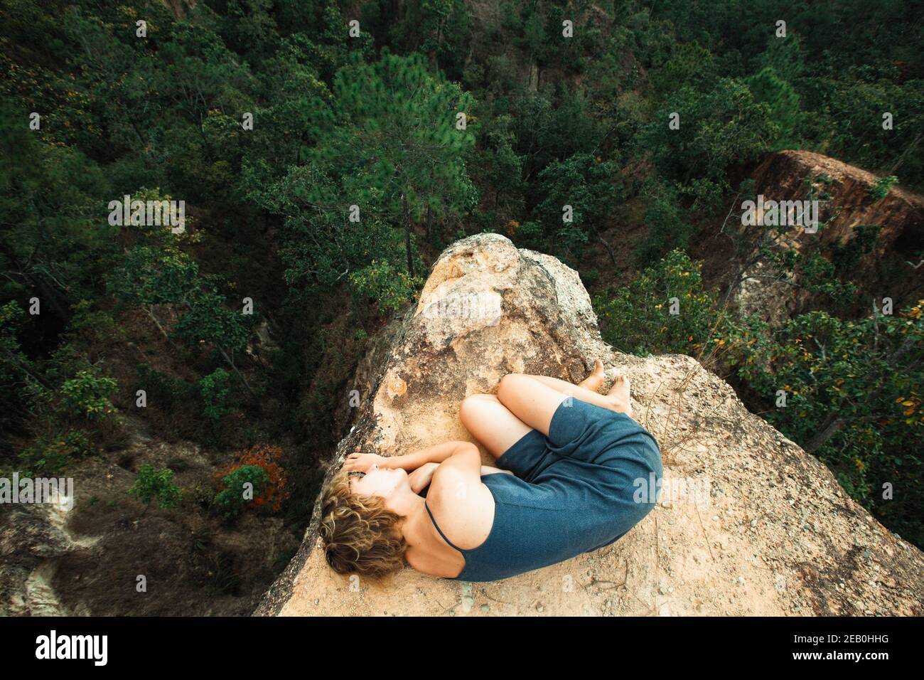 Young girl lying curled up on top of the rock in the canyon Stock Photo ...