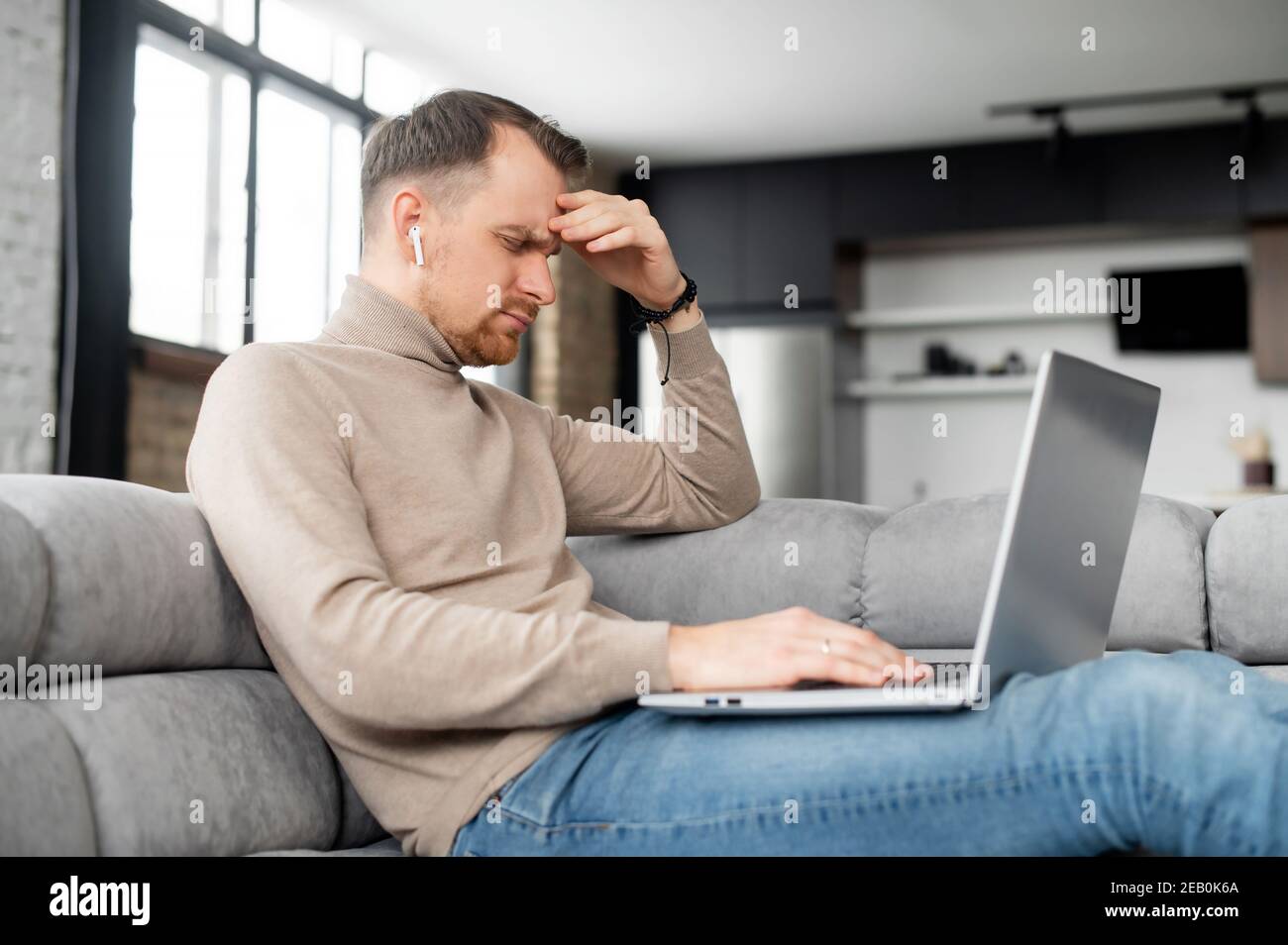 The guy working remotely has a headache, young man with laptop holding ...