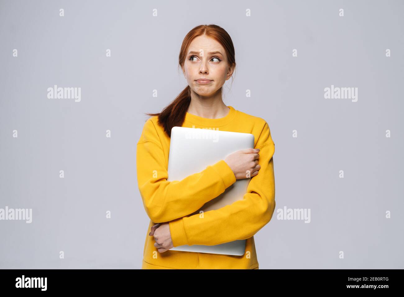 Happy young woman student holding laptop computer and looking away on ...
