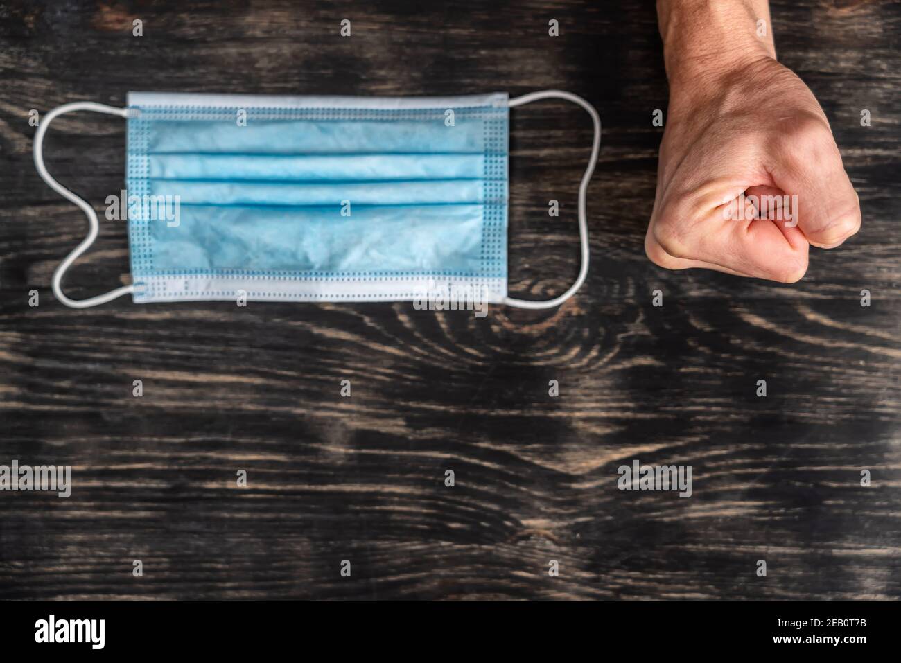 Surgical mask placed on a table and a clenched fist beside it to ...