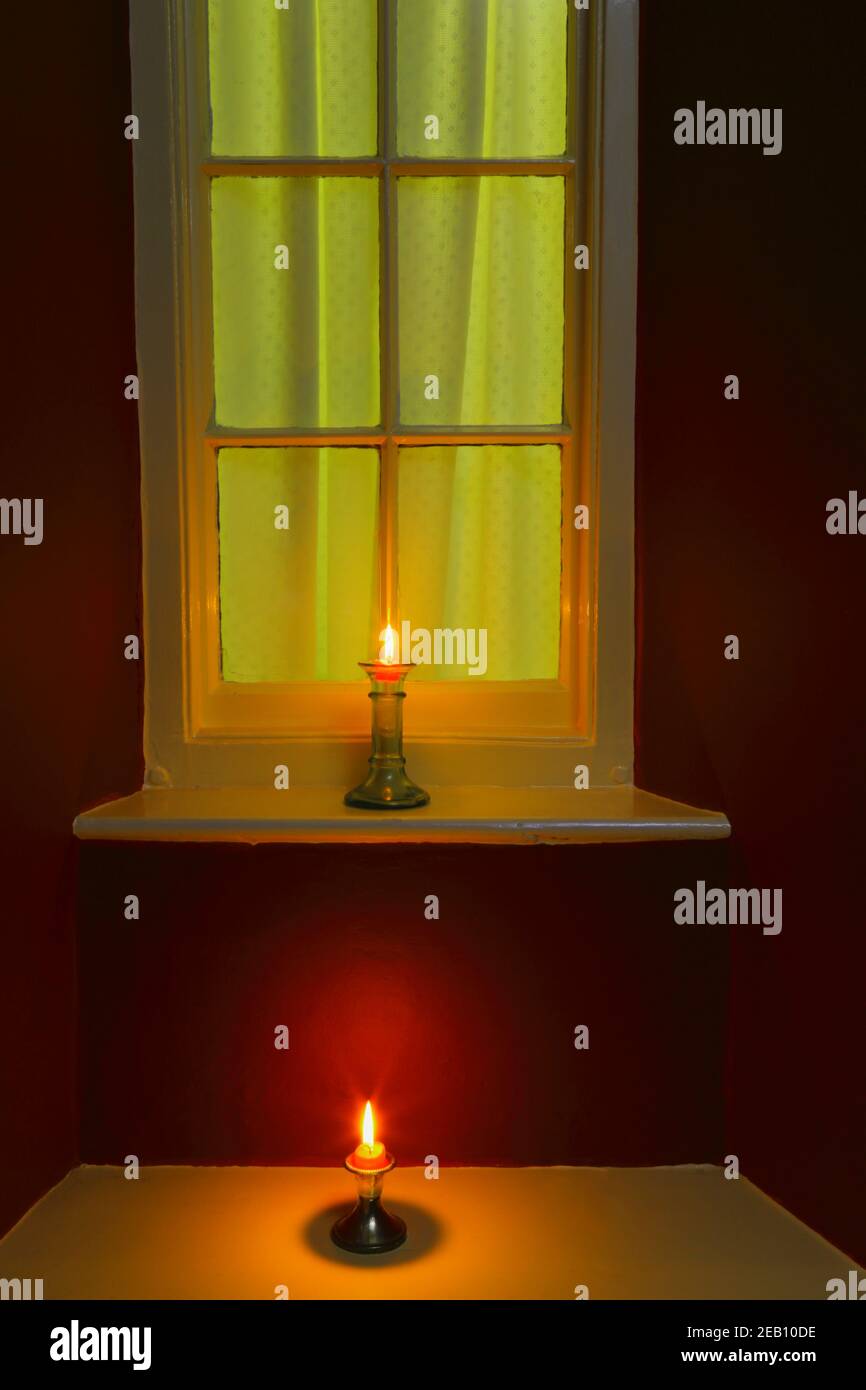Two candles burning near window Stock Photo - Alamy
