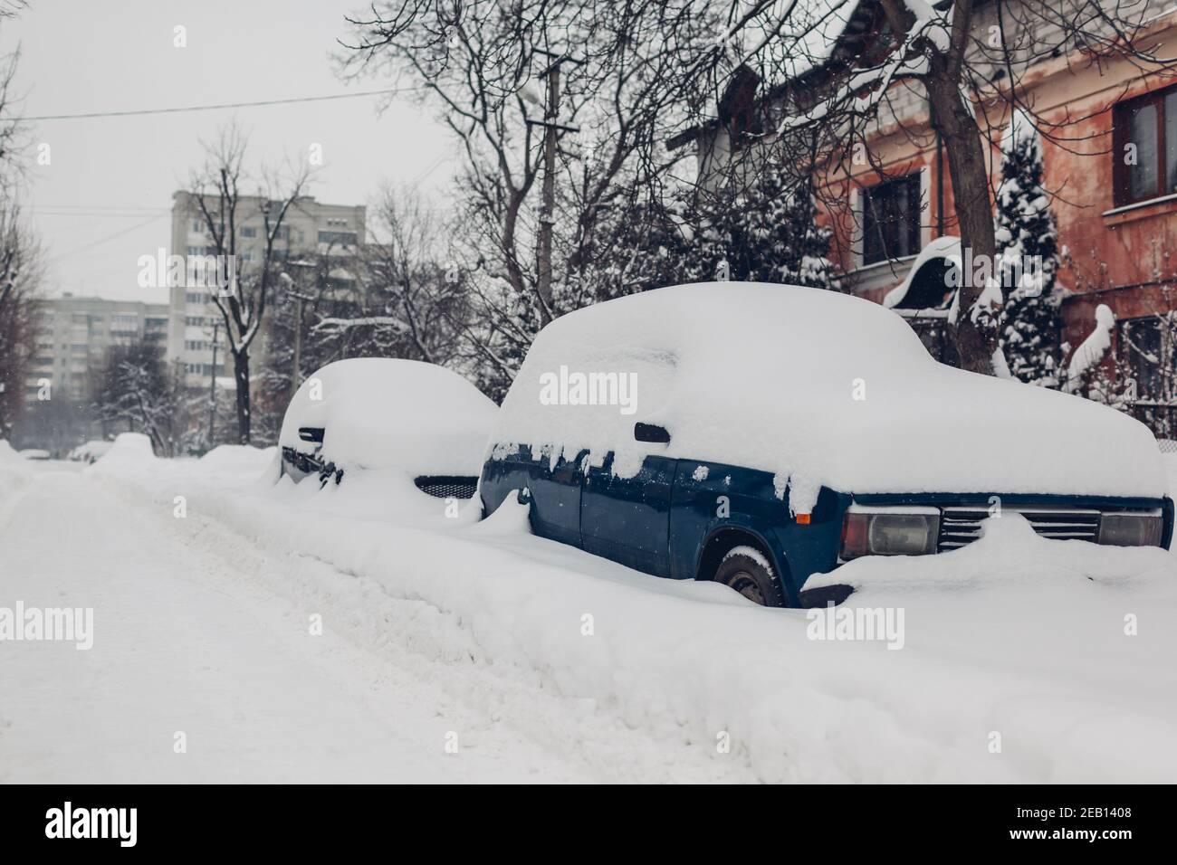 Cars covered with snow during snowfall in city. Automobiles stuck in ...