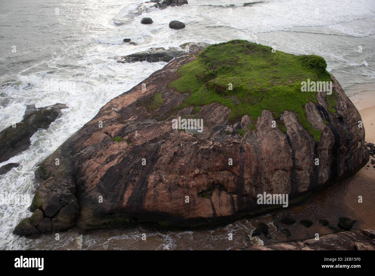 Massive mossy rock at the beach washed by ocean waves Stock Photo - Alamy