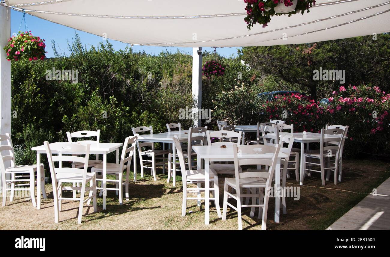Rustic outdoor cafe with wooden white tables and chairs under the ...