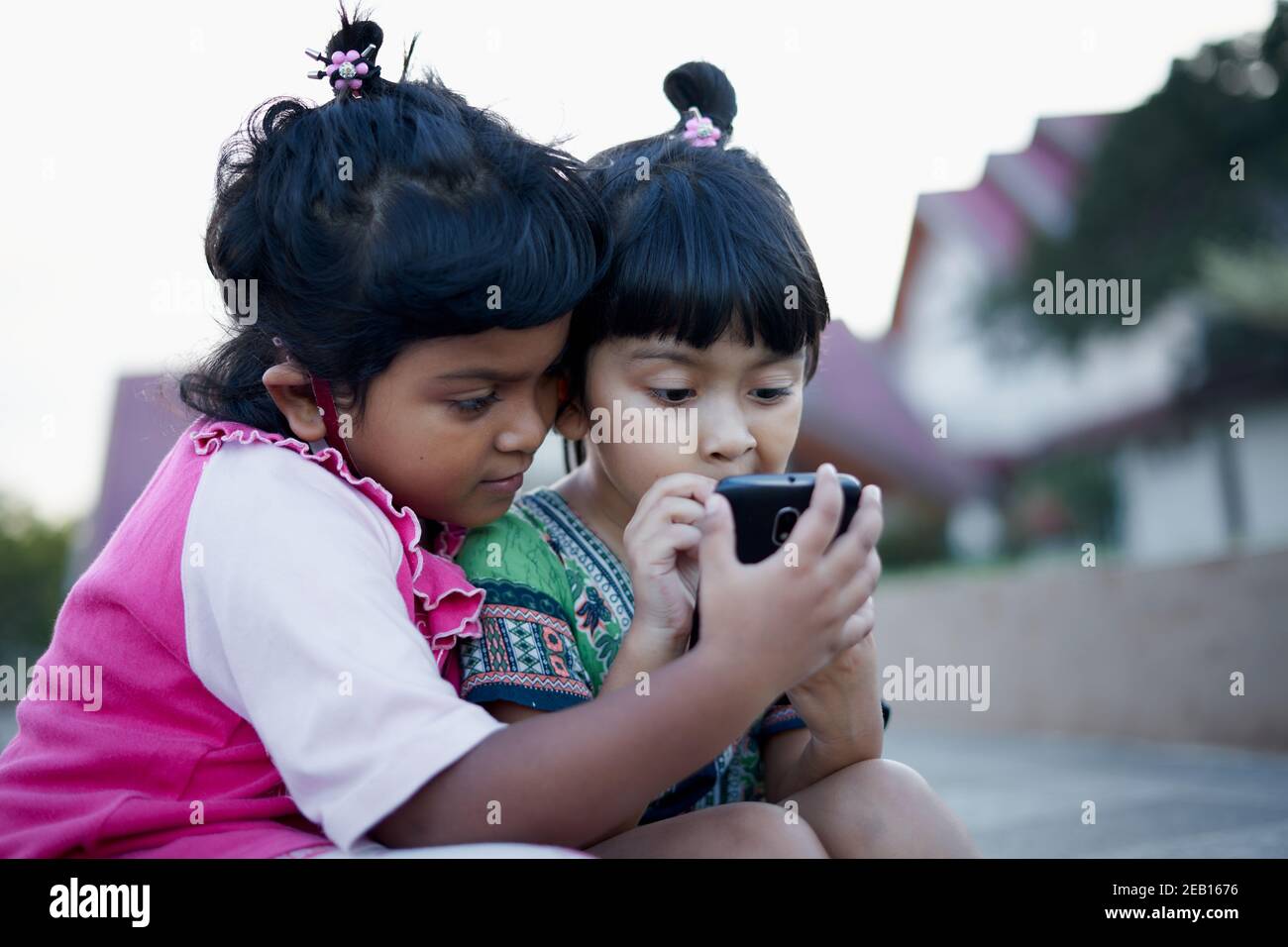 Two little Girls playing and learning with their smartphone at public ...