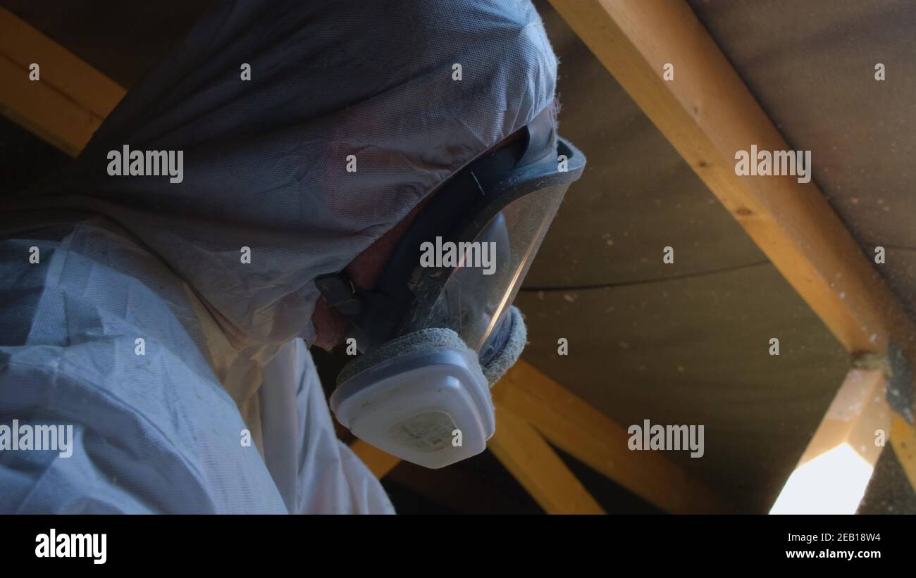Man in respirator mask making thermal roof insulation. Full-face ...