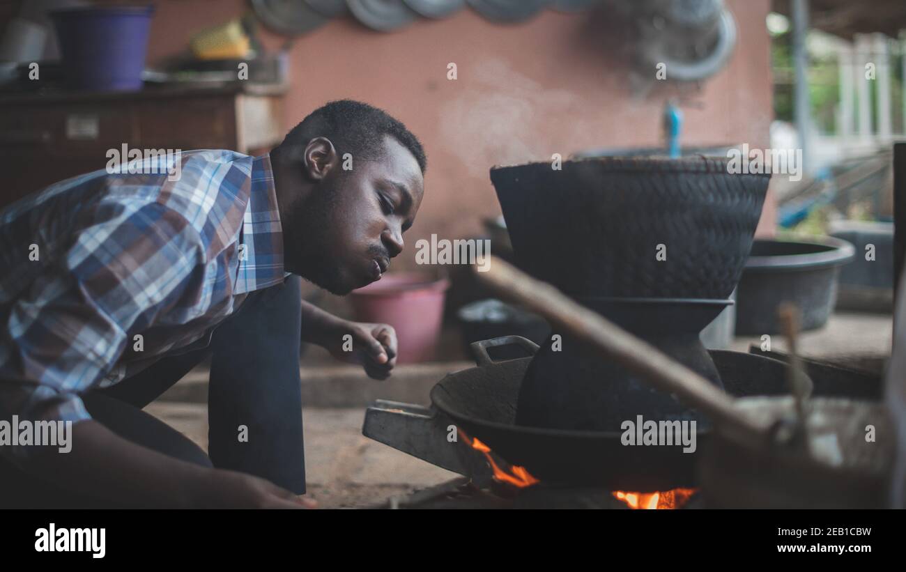 African man sitting to blow fire to cook rice.16:9 style Stock Photo ...