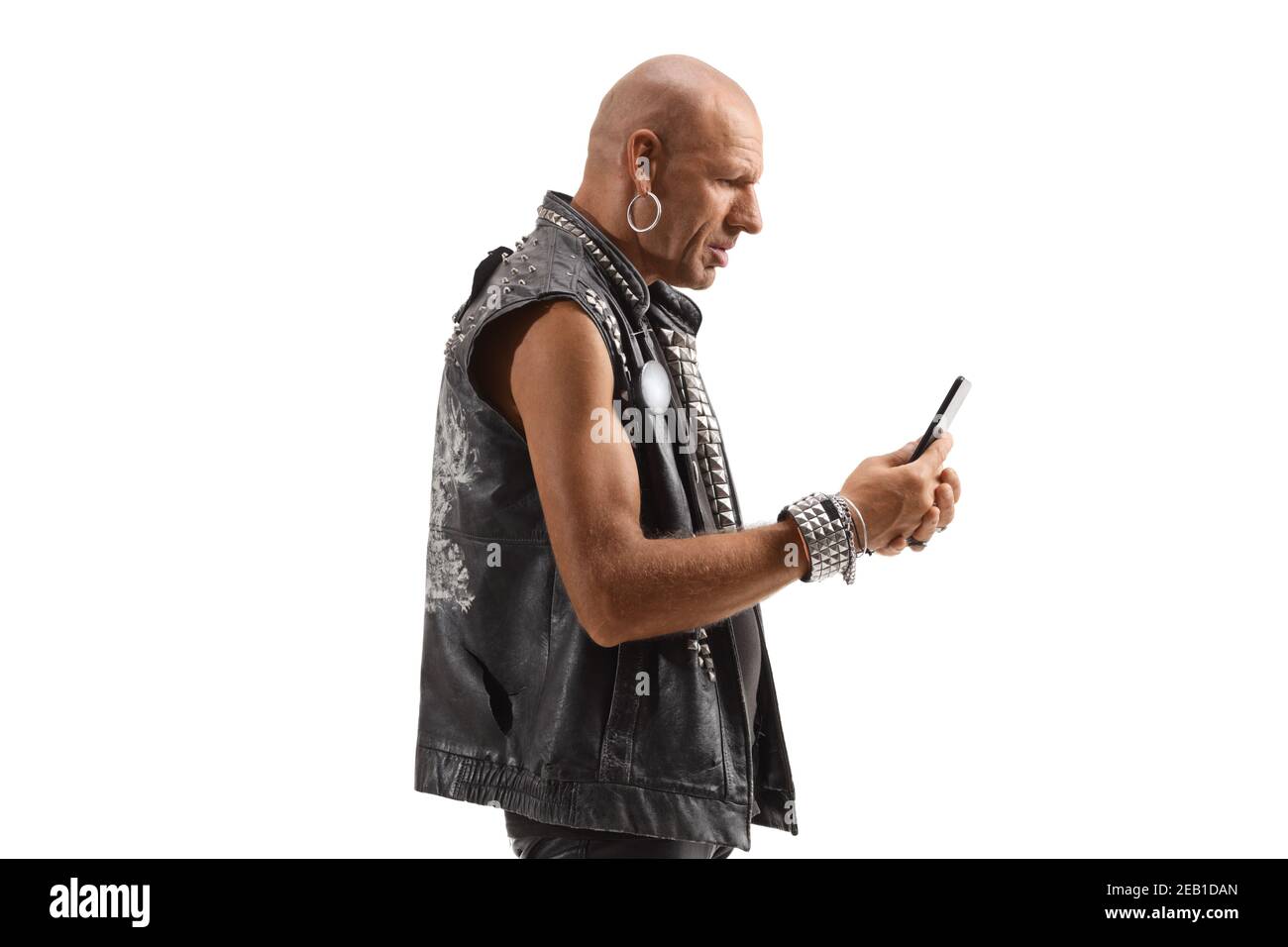 Punk in a leather vest standing and typing on a mobile phone isolated ...