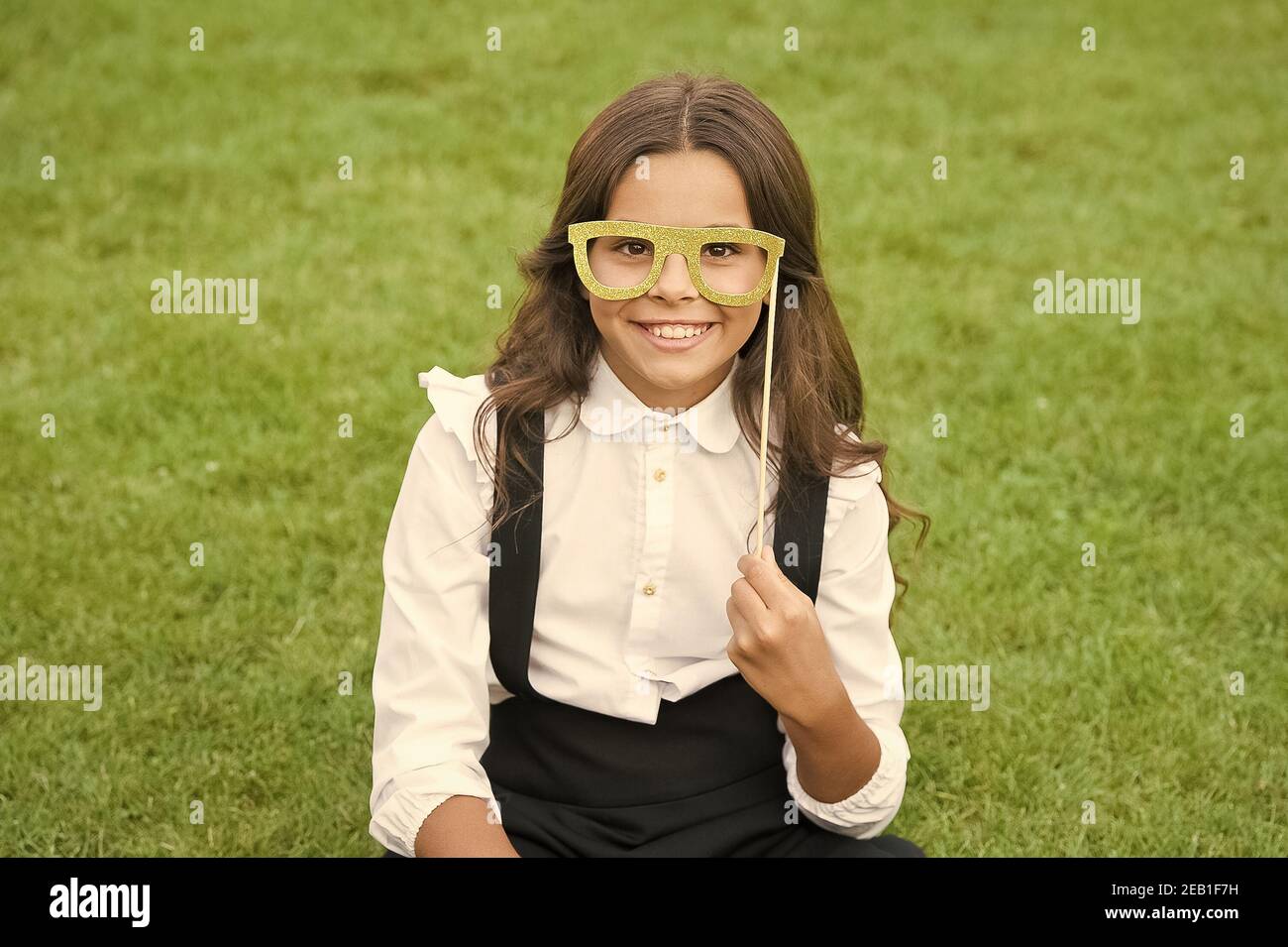 School party. Happy child hold prop glasses. Party girl on green grass ...
