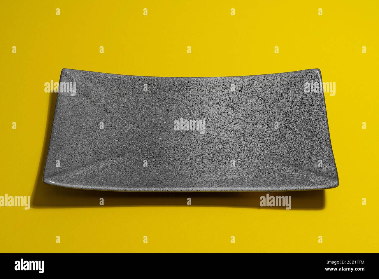 empty dark plate on yellow background Stock Photo - Alamy