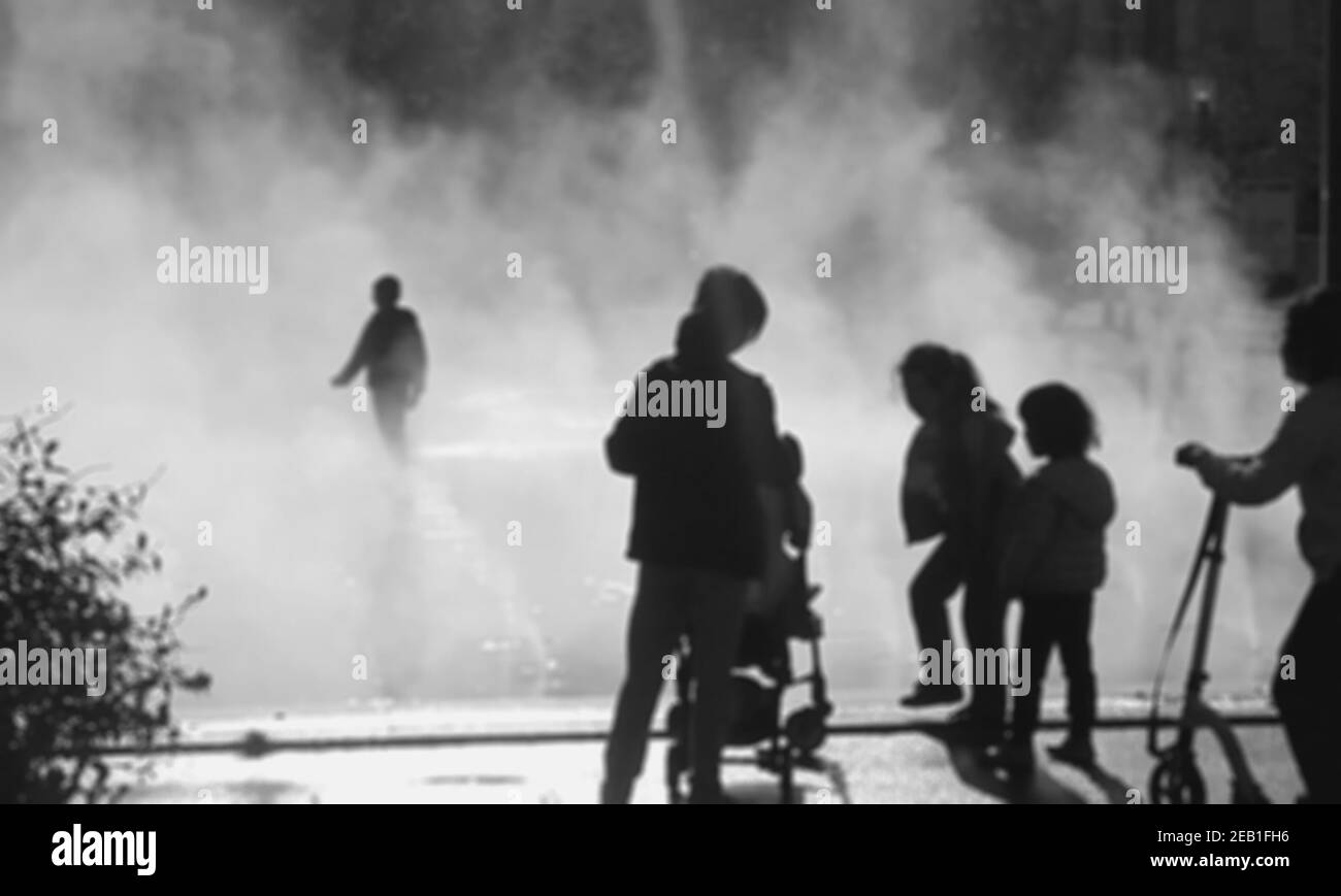 Blurred photo of children playing in fountain water mist and their ...