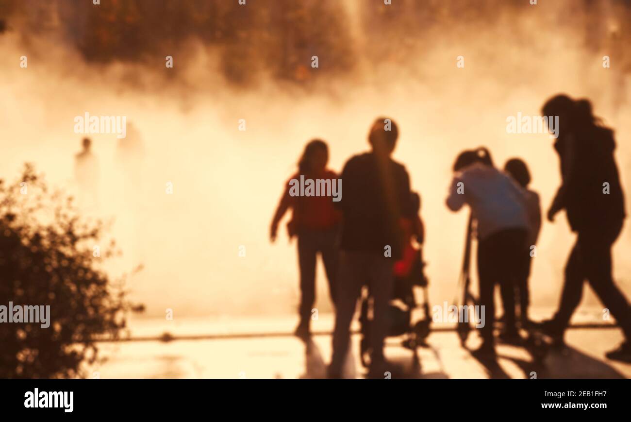 Blurred photo of kids playing in fountain water mist and their mothers ...