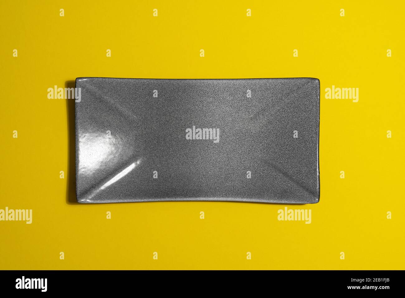 empty dark plate on yellow background Stock Photo - Alamy