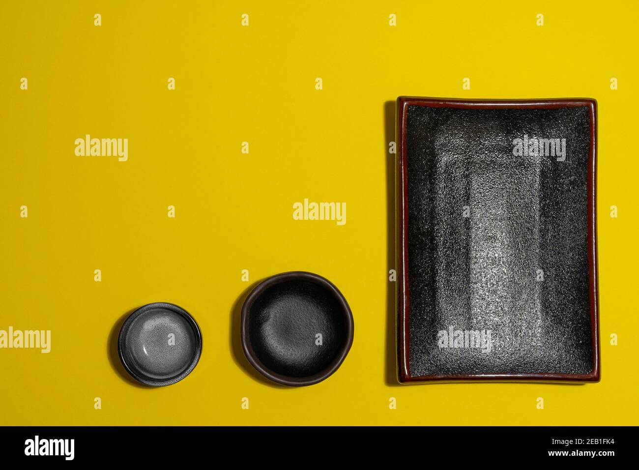 three empty dark plates on yellow background Stock Photo - Alamy