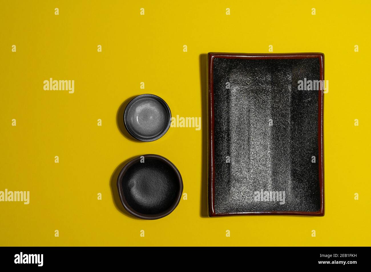 three empty dark plates on yellow background Stock Photo - Alamy