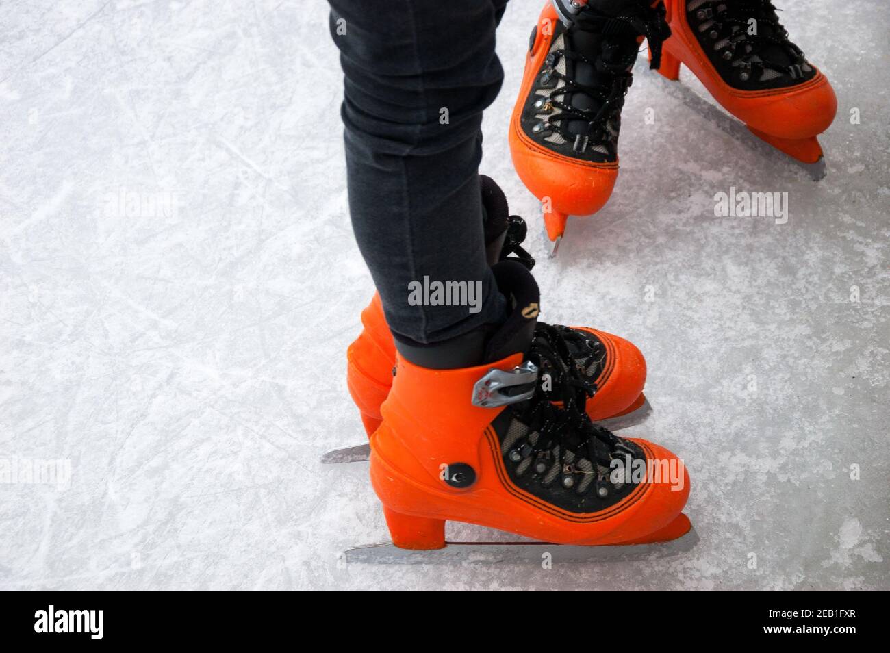 Two girls wearing orange skates on ice rink. Beginner skaters Stock ...