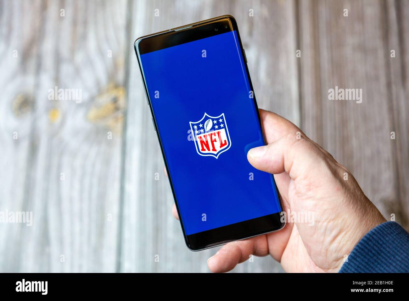 A mobile phone or cell phone being held by a hand with the NFL app open ...