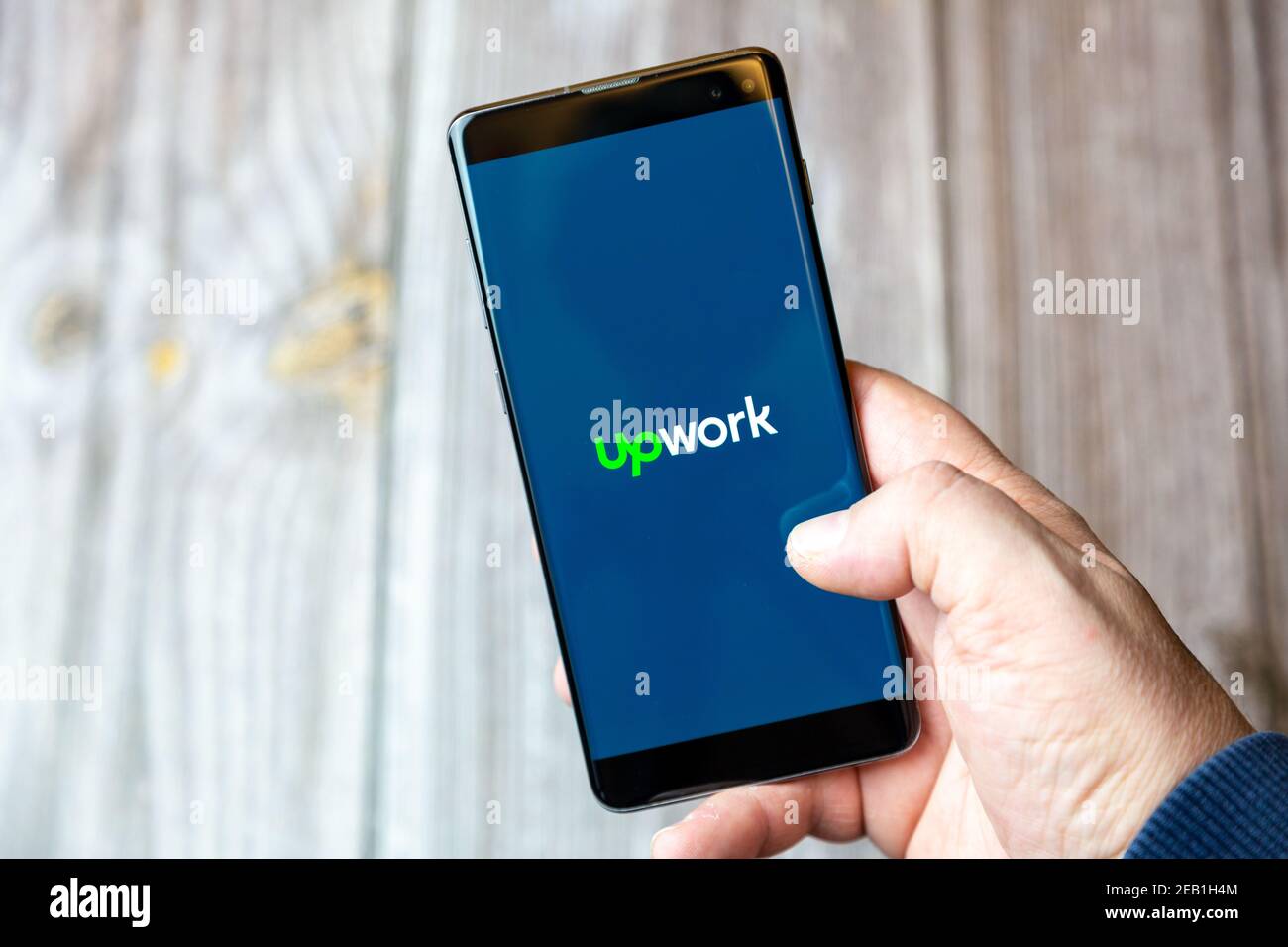 A mobile phone or cell phone being held by a hand with the Upwork app ...
