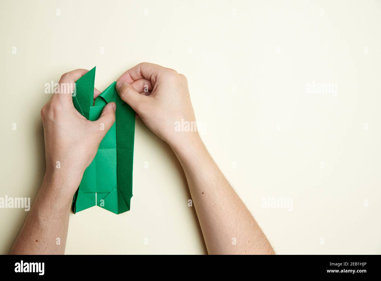 Creation process of an origami clover: young hands folding a green ...