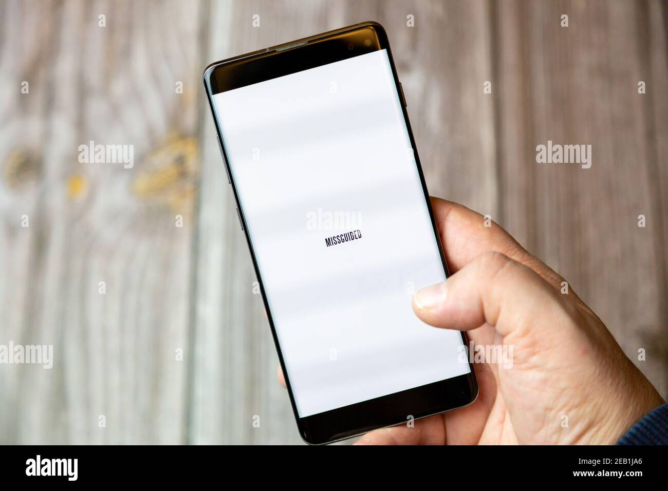 A mobile phone or cell phone being held by a hand with the Missguided ...