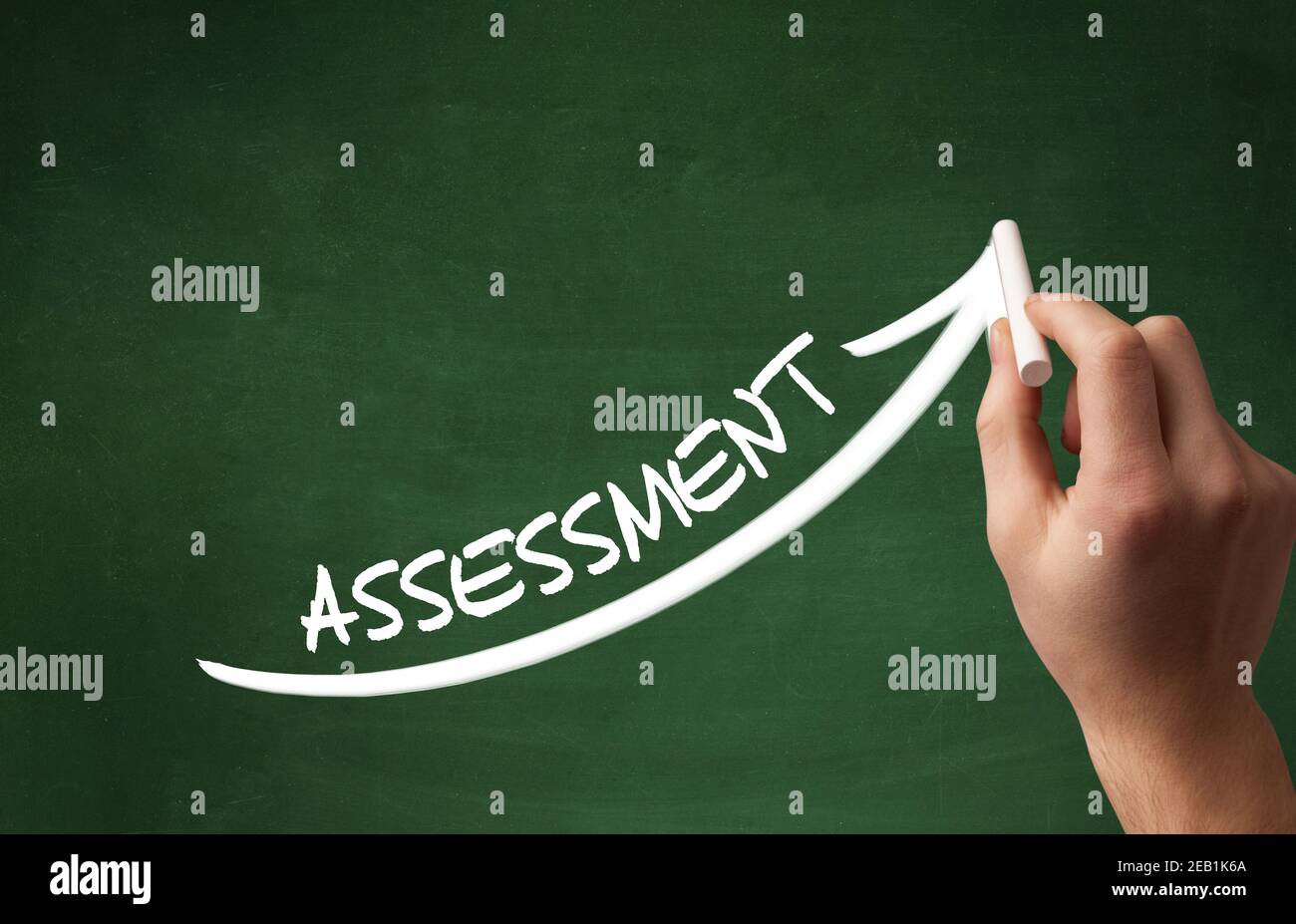 Hand drawing ASSESSMENT inscription with white chalk on blackboard ...