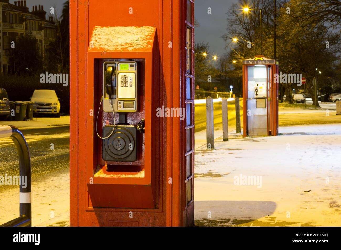Red cast iron telephone box with BT telephone standing in the snow with ...