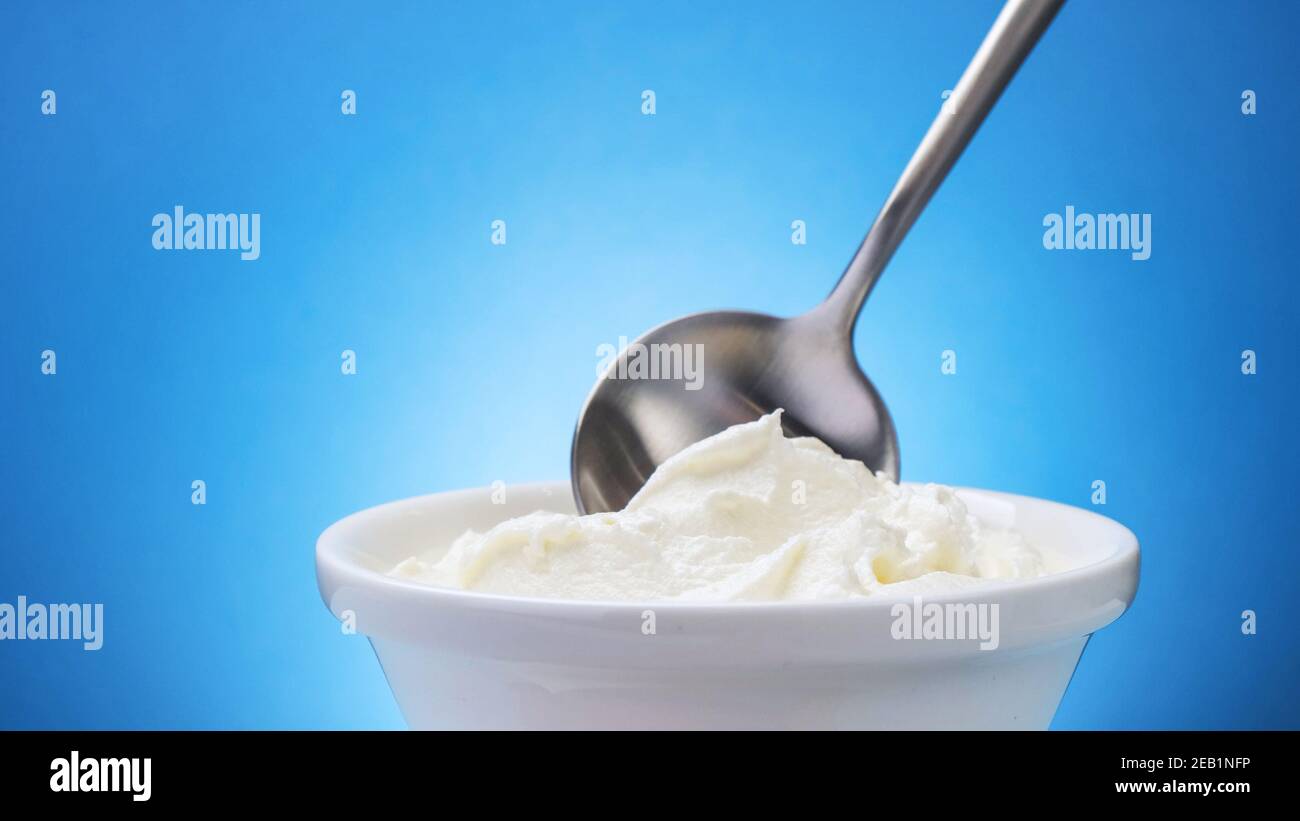 Whipped cream with spoon on blue background Stock Photo - Alamy