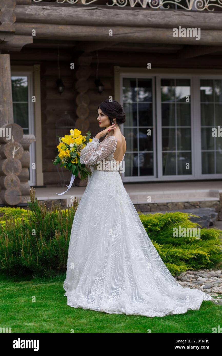 The charming bride keeps a wedding bouquet and posing on yard Stock ...