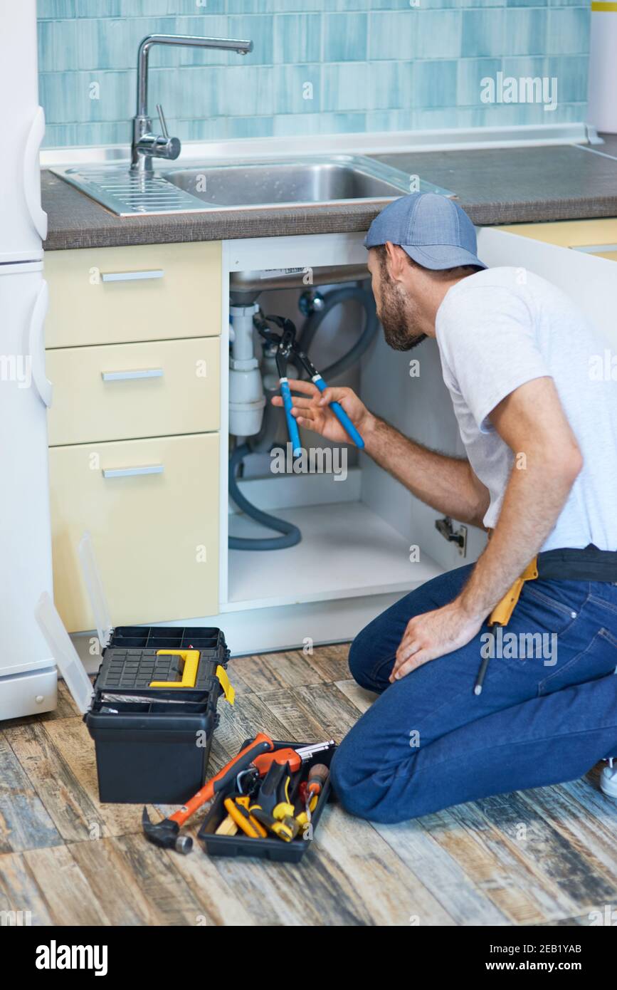 Plumbing troubles. Professional plumber using pipe wrench while ...