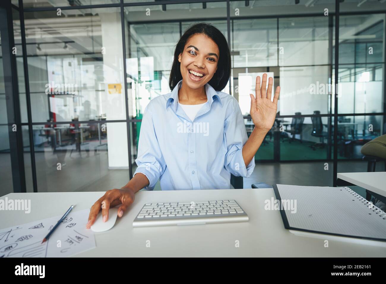 Beautiful young lady greeting someone on video-call Stock Photo - Alamy