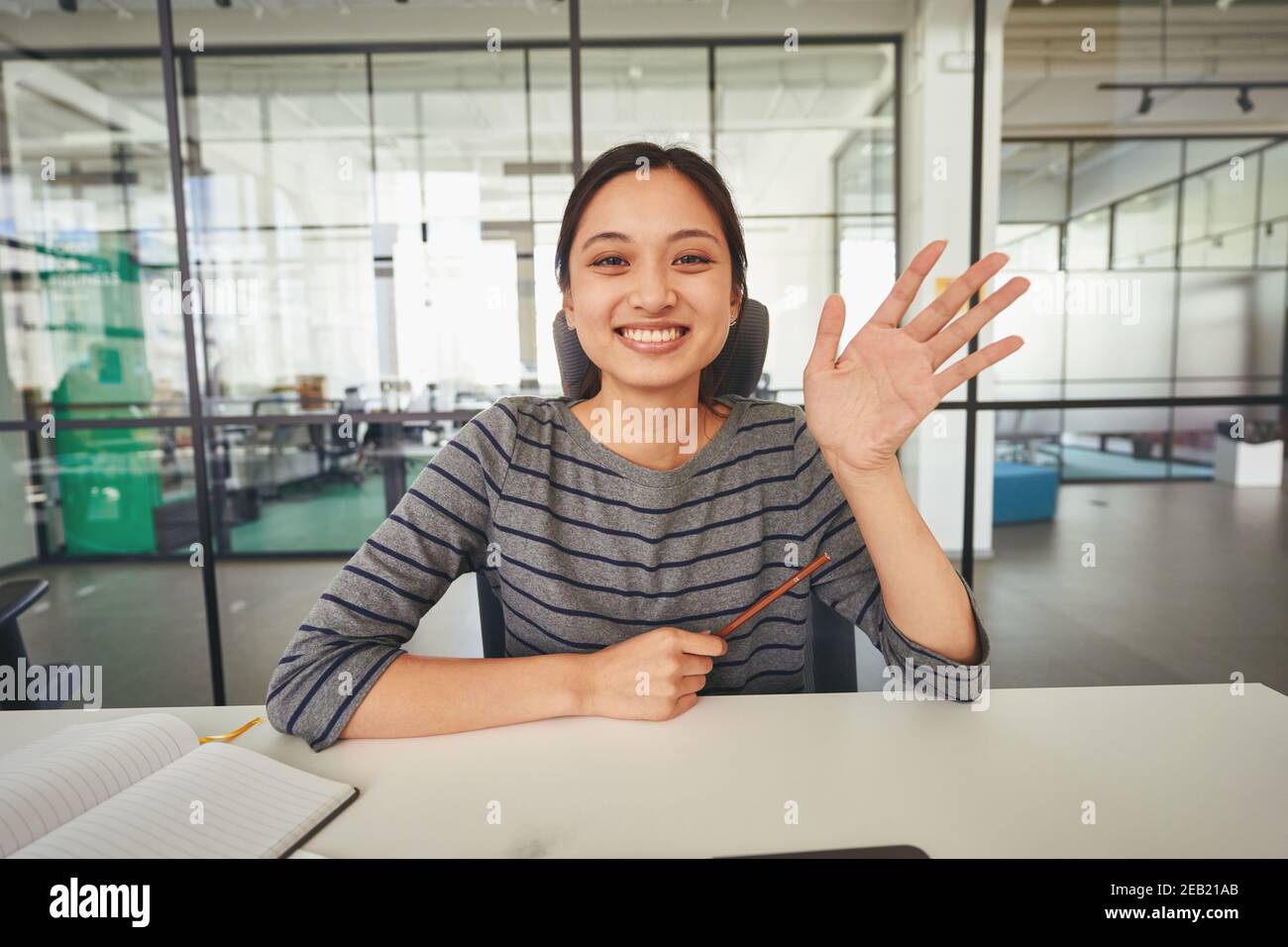 Easy-going woman sitting at table and waving her hand Stock Photo - Alamy