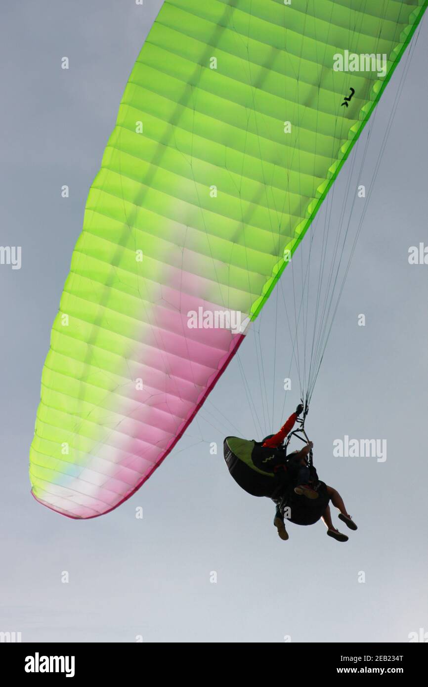Two persons paragliding high in the sky, illuminated colorful cloth ...