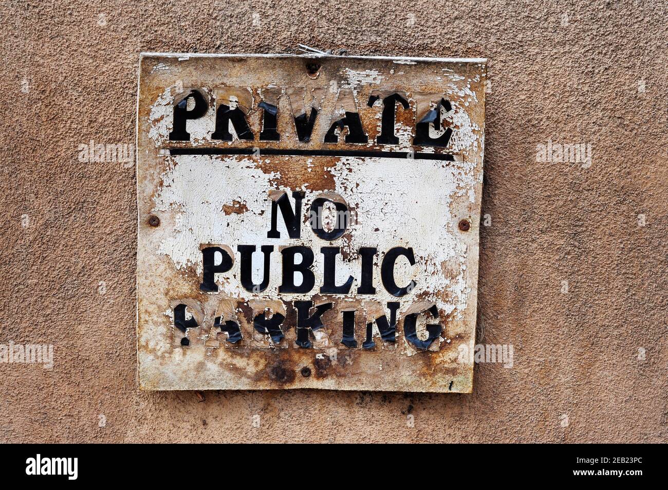 A weathered and stained no parking sign on an adobe wall in Santa Fe ...