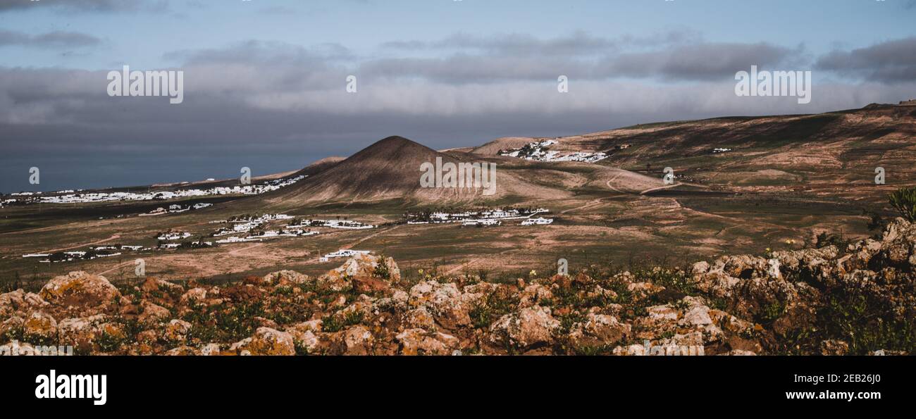 Rural field and hills covered by rocks under the cloudy sky Stock Photo ...