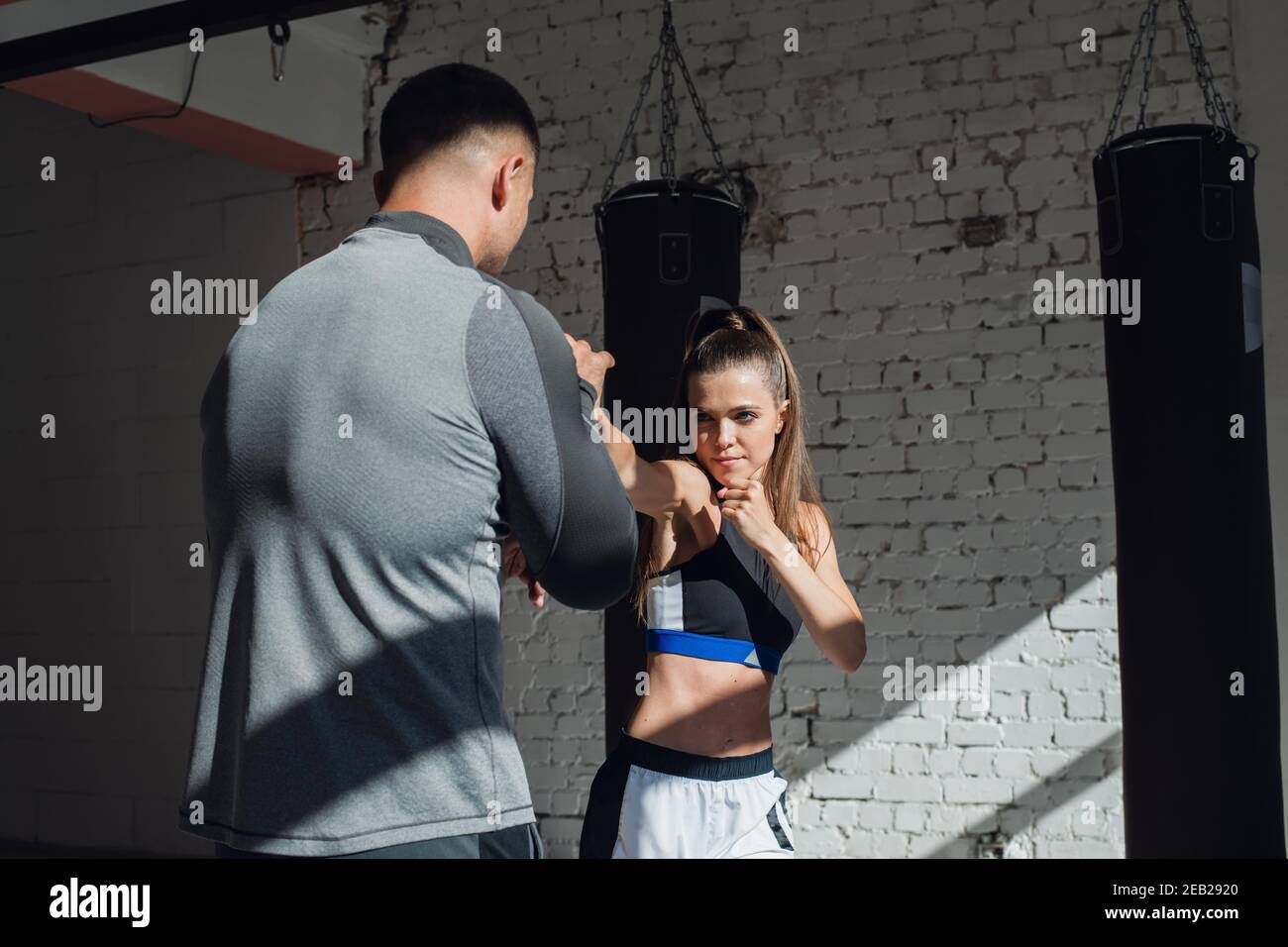 A young attractive boxing coach prepares a pretty girl for competition ...