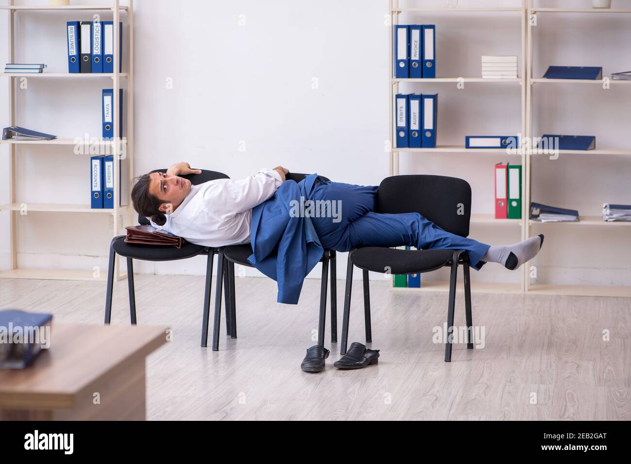 Young employee sleeping in the office on chairs Stock Photo - Alamy