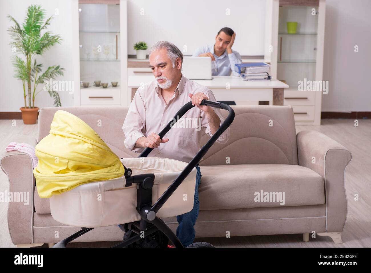 Old grandfather looking after newborn at home Stock Photo - Alamy