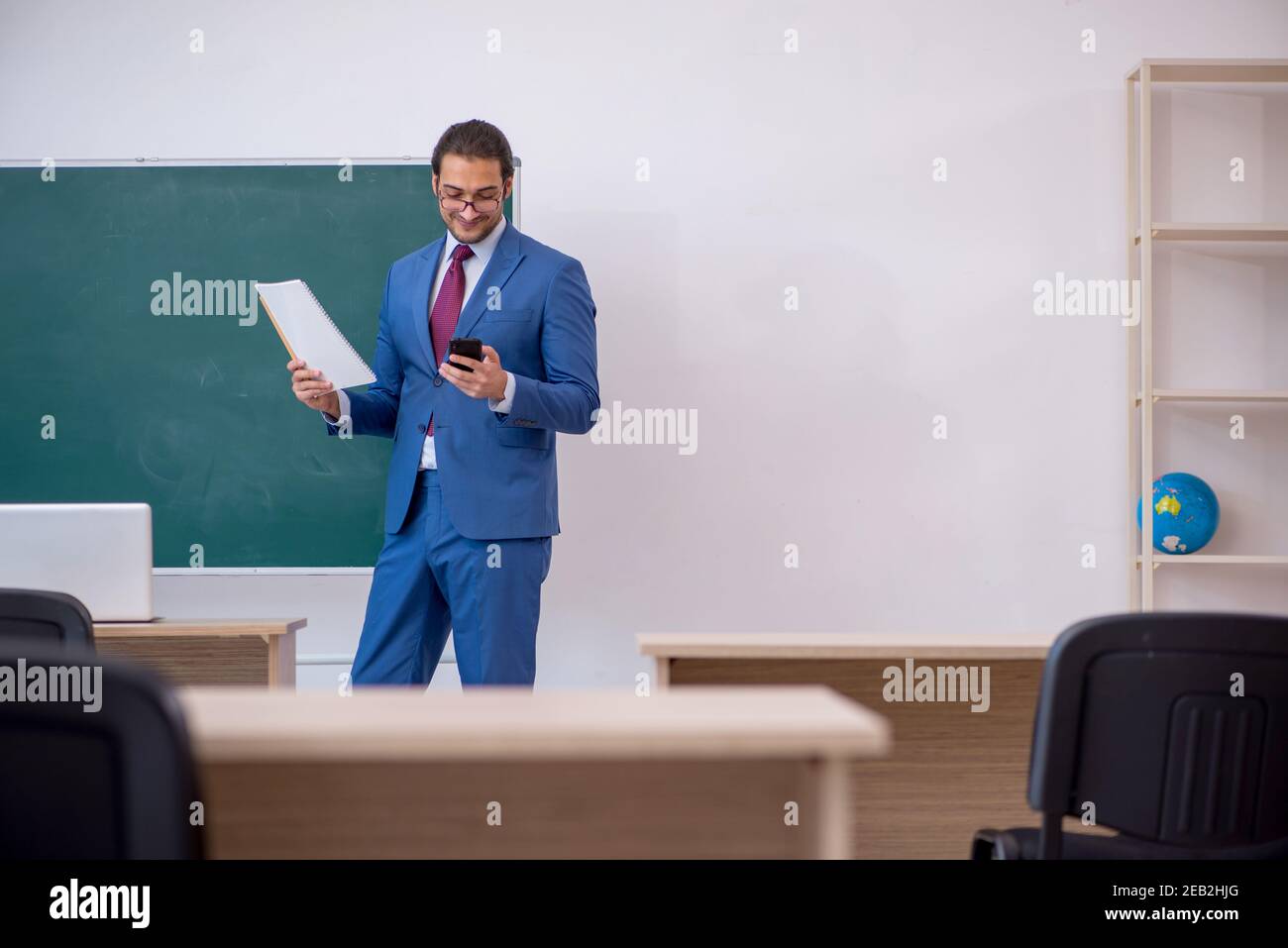 Young teacher in suit in front of green board Stock Photo - Alamy
