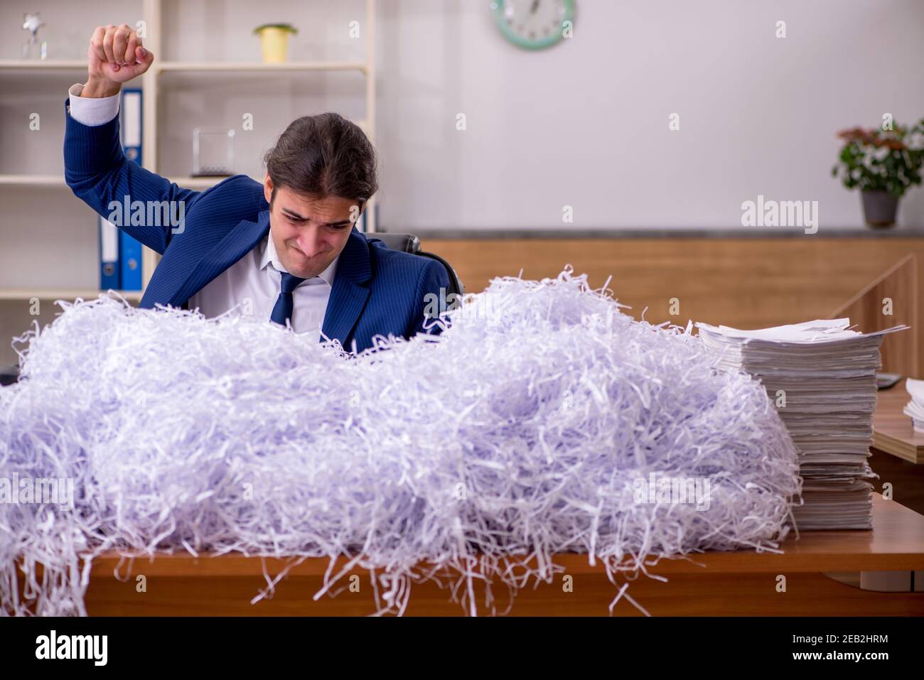 Young male employee cutting papers in the office Stock Photo - Alamy
