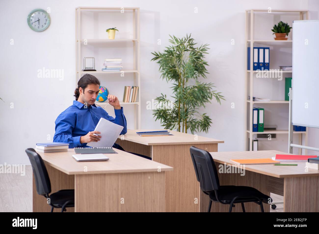 Young teacher checking notes in the classroom Stock Photo - Alamy