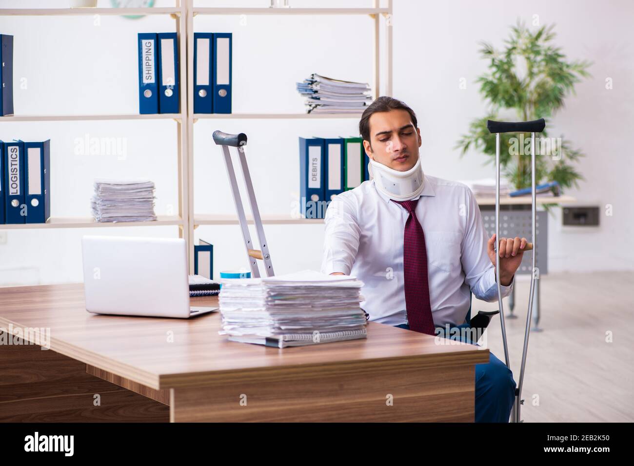 Leg injured employee with crutches at workplace Stock Photo - Alamy