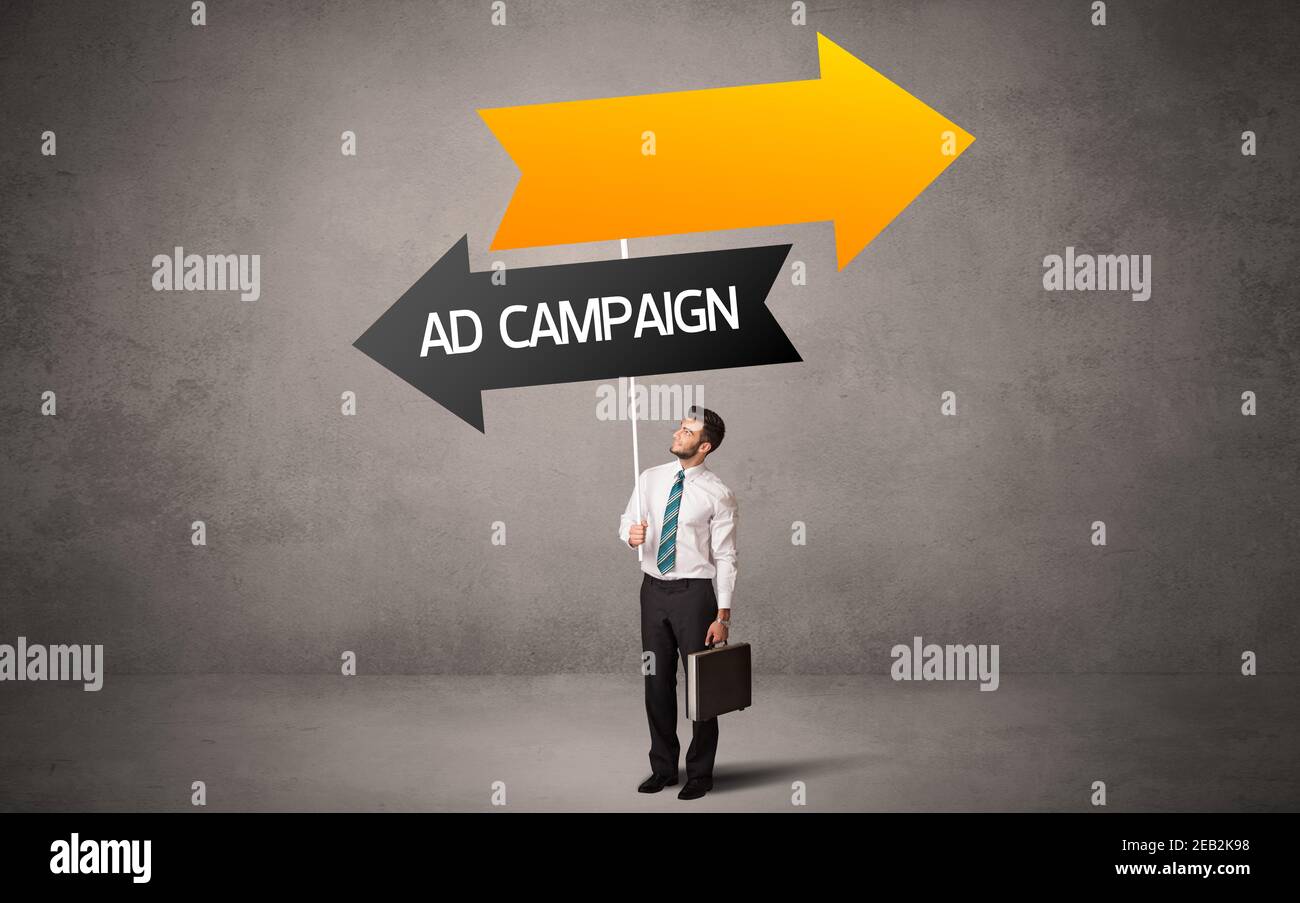 Young business person in casual holding road sign with AD CAMPAIGN ...