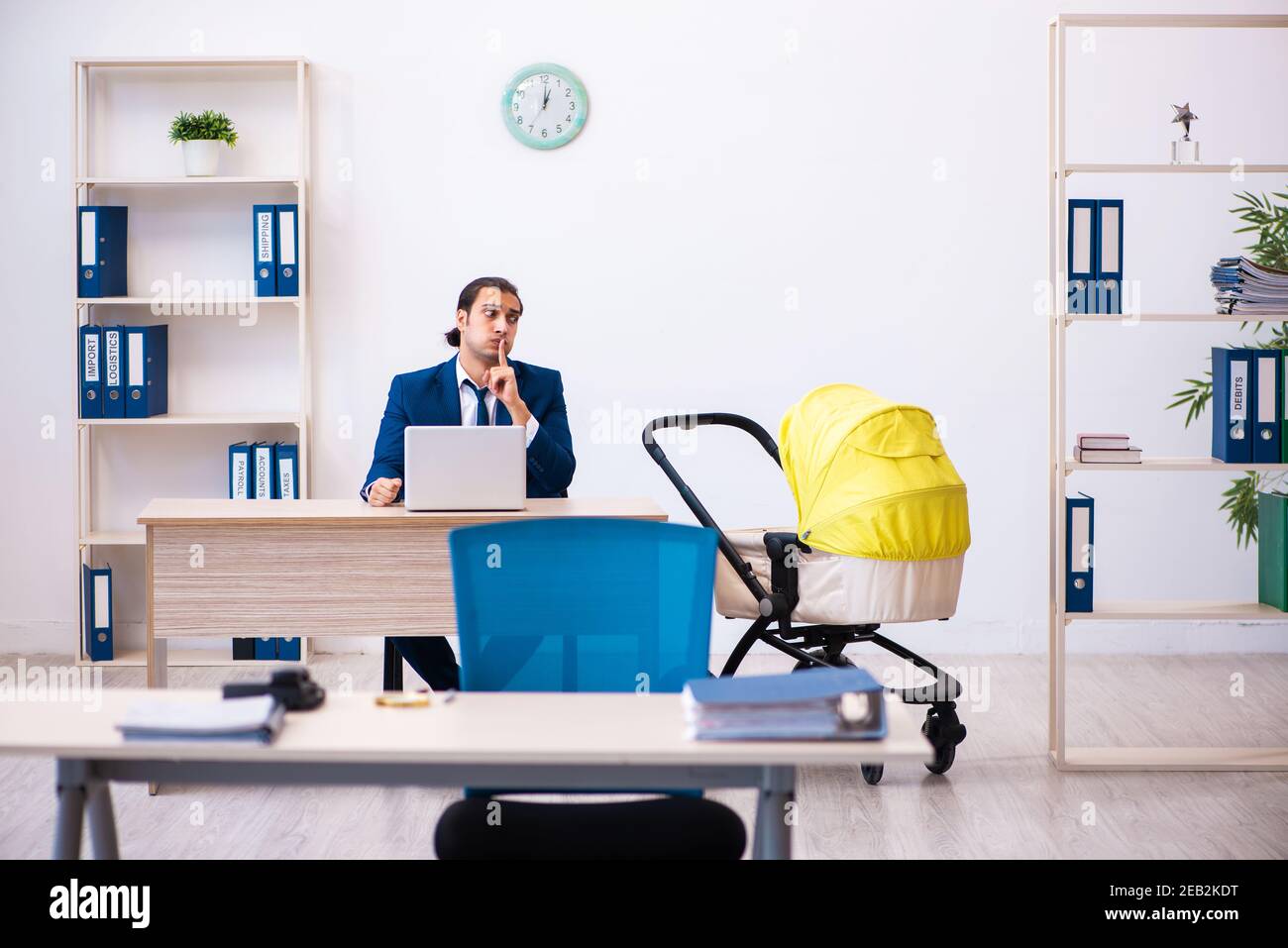 Young employee looking after kid at workplace Stock Photo - Alamy