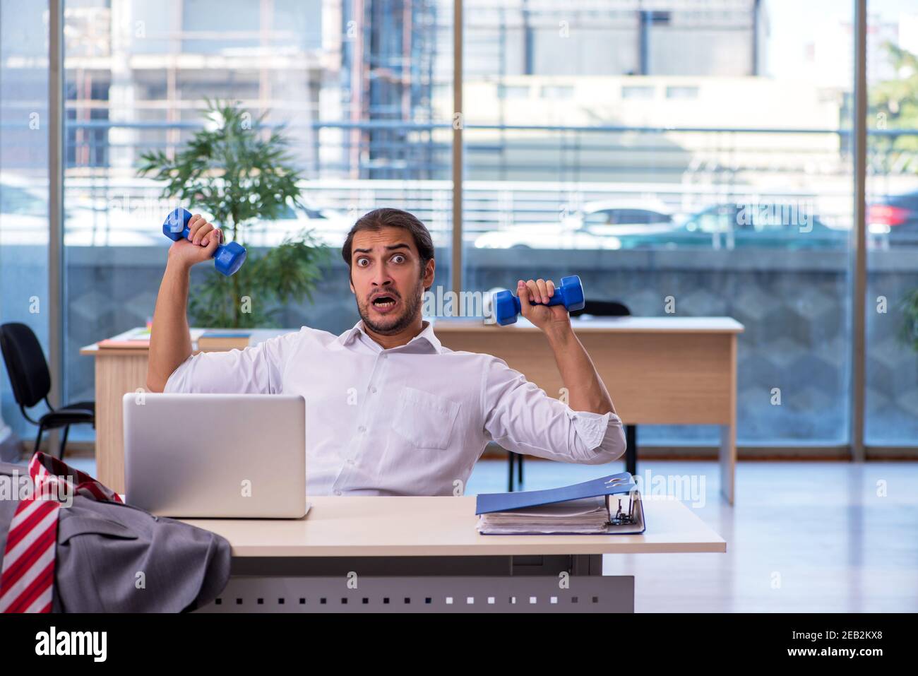 Young employee doing sport exercises at workplace Stock Photo - Alamy