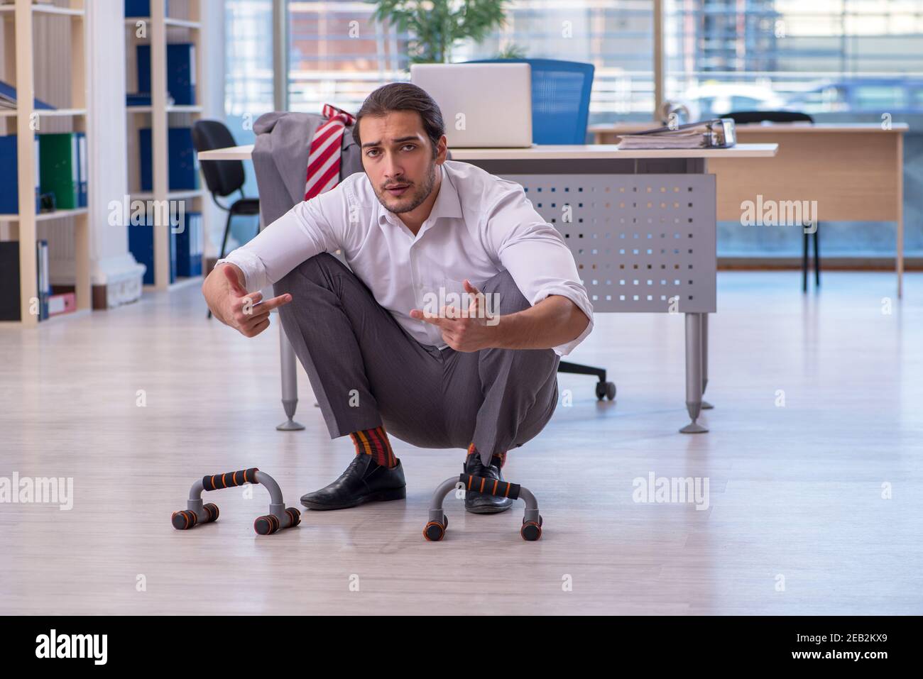 Young employee doing sport exercises at workplace Stock Photo - Alamy