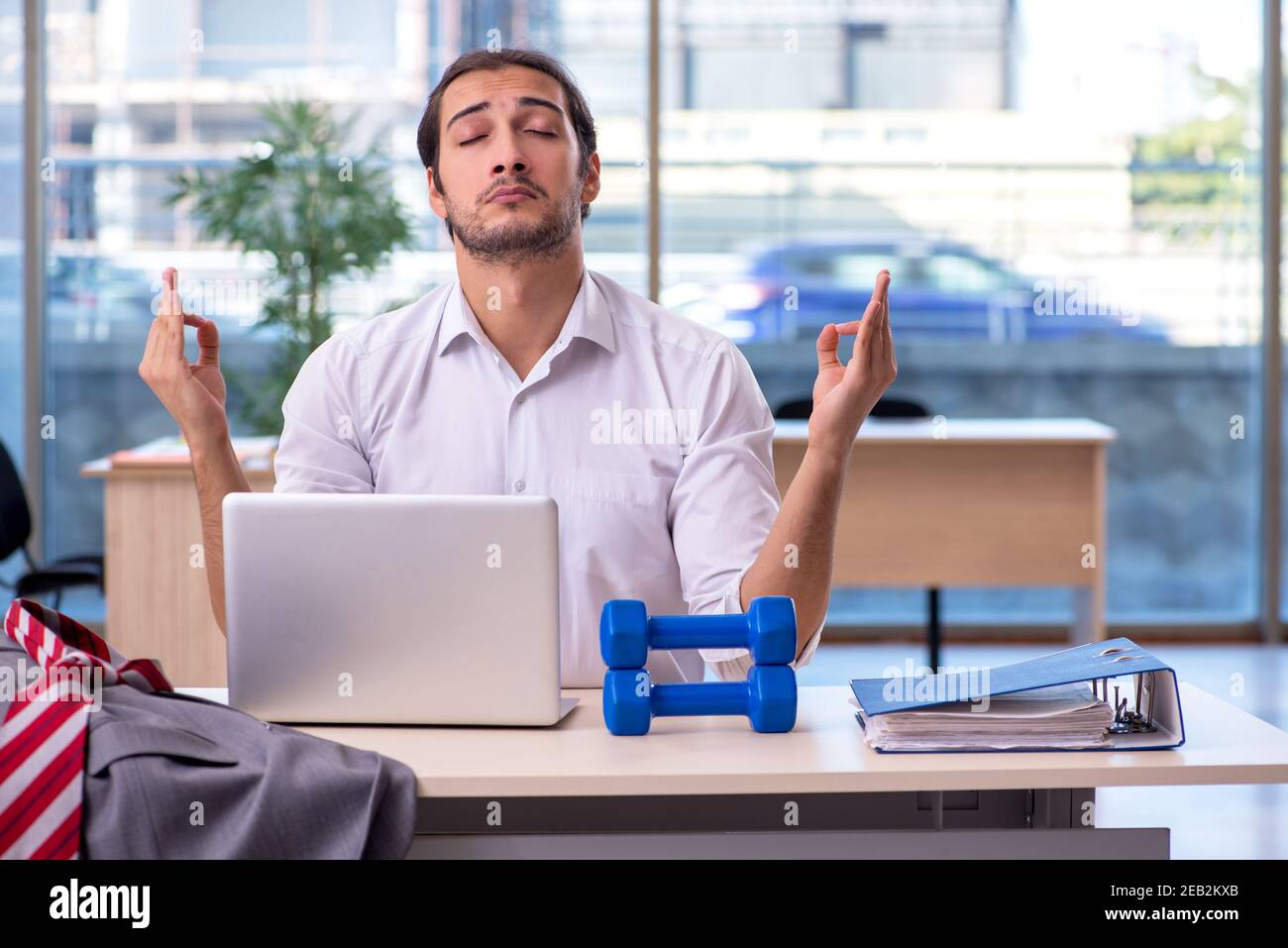 Young employee doing sport exercises at workplace Stock Photo - Alamy